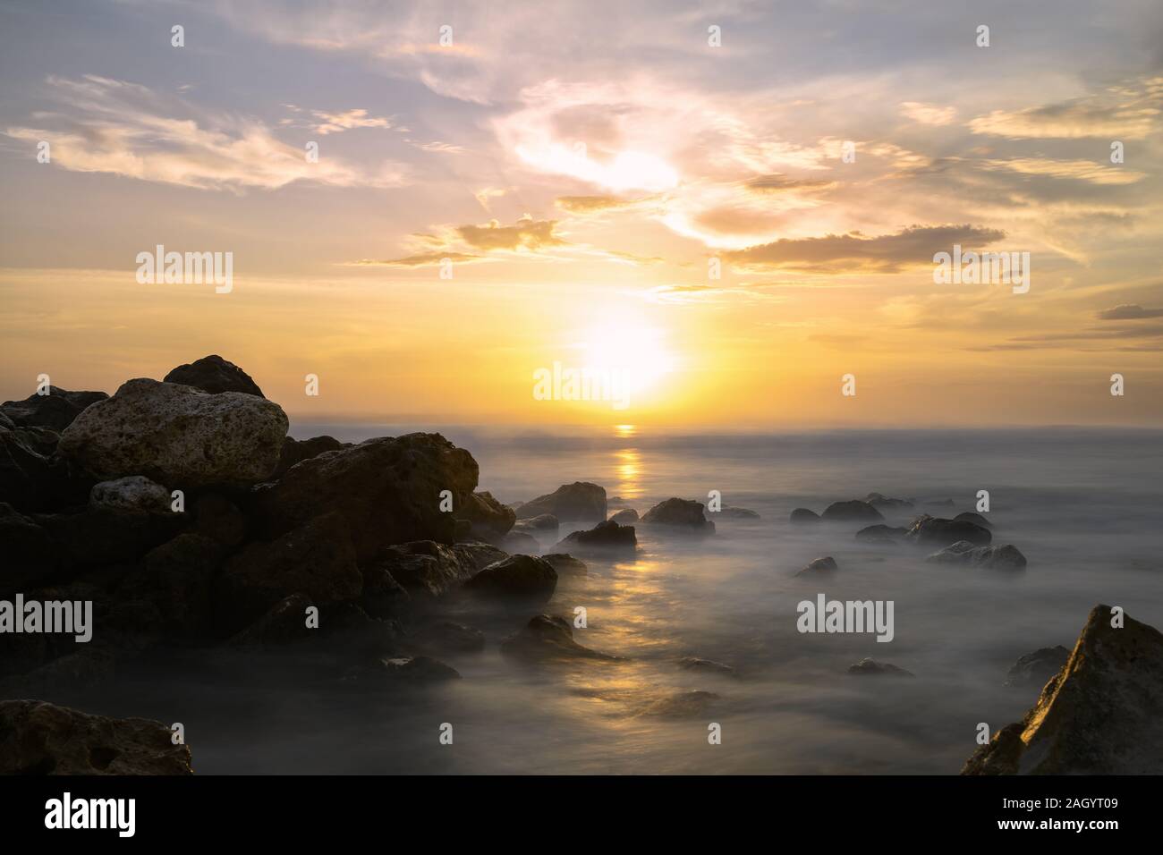 Stunning view of a rocky coast bathed by a smooth silky sea during a ...
