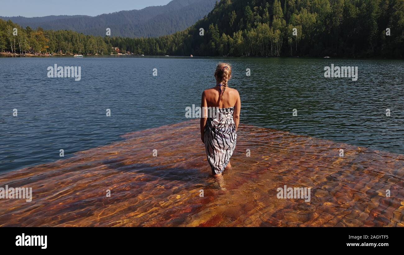 Woman walk on water on pier in sunglasses and a boho silk shawl. Girl ...