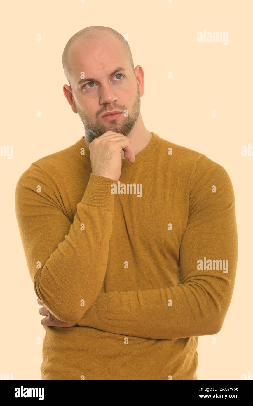 Studio shot of young bald muscular man thinking while looking up Stock ...