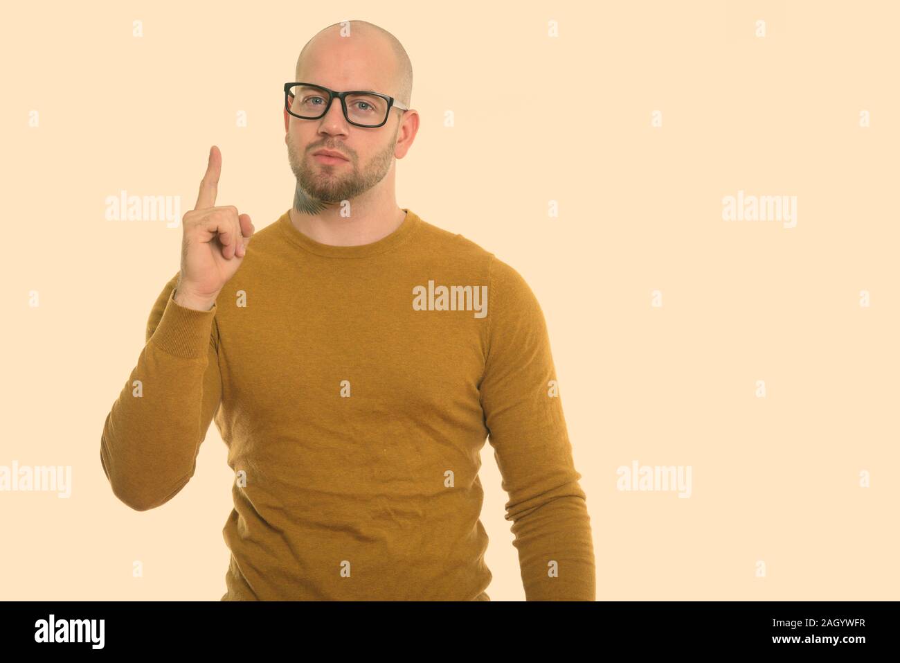 Studio shot of young bald muscular man pointing finger up Stock Photo ...