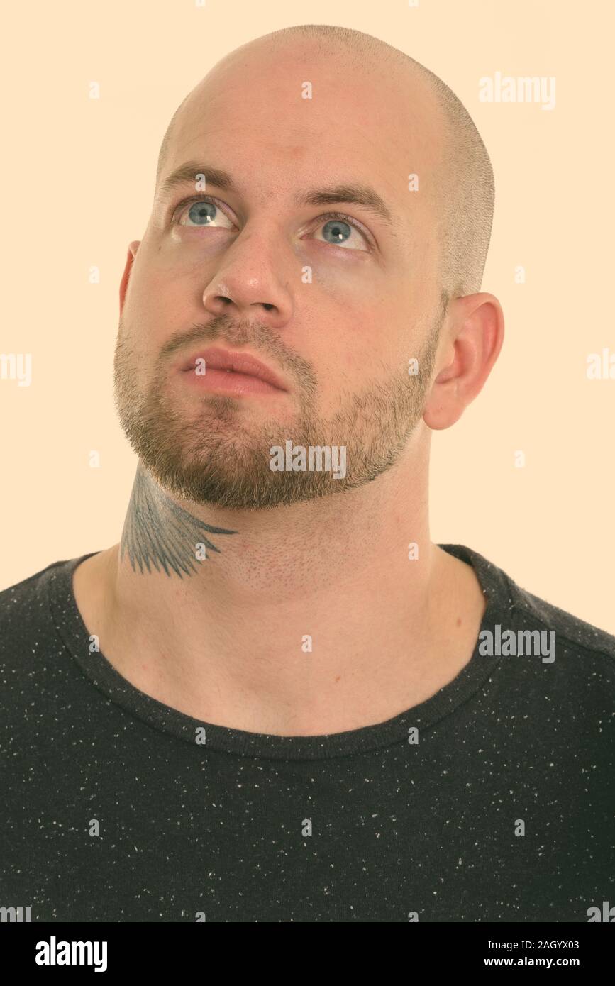 Face of young bald muscular man thinking while looking up Stock Photo ...
