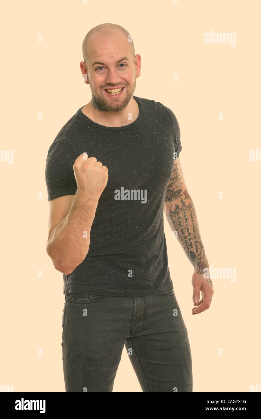 Studio shot of young happy bald muscular man smiling while looking ...