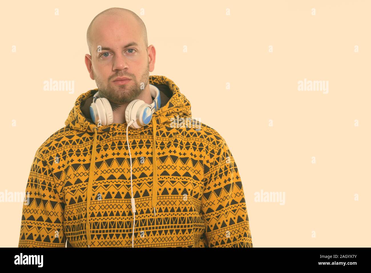 Studio shot of young bald muscular man wearing headphones around neck ...