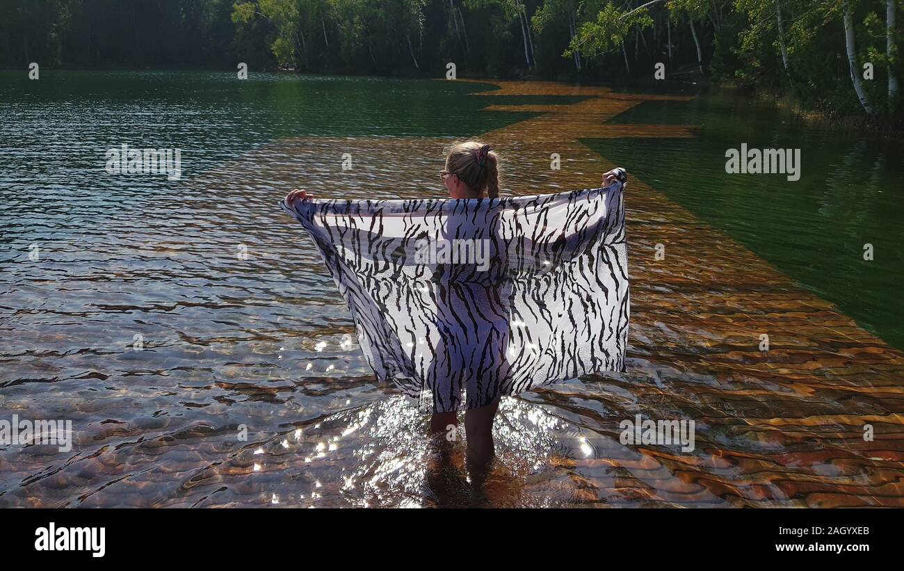Woman walk on water on pier in sunglasses and a boho silk shawl. Girl ...