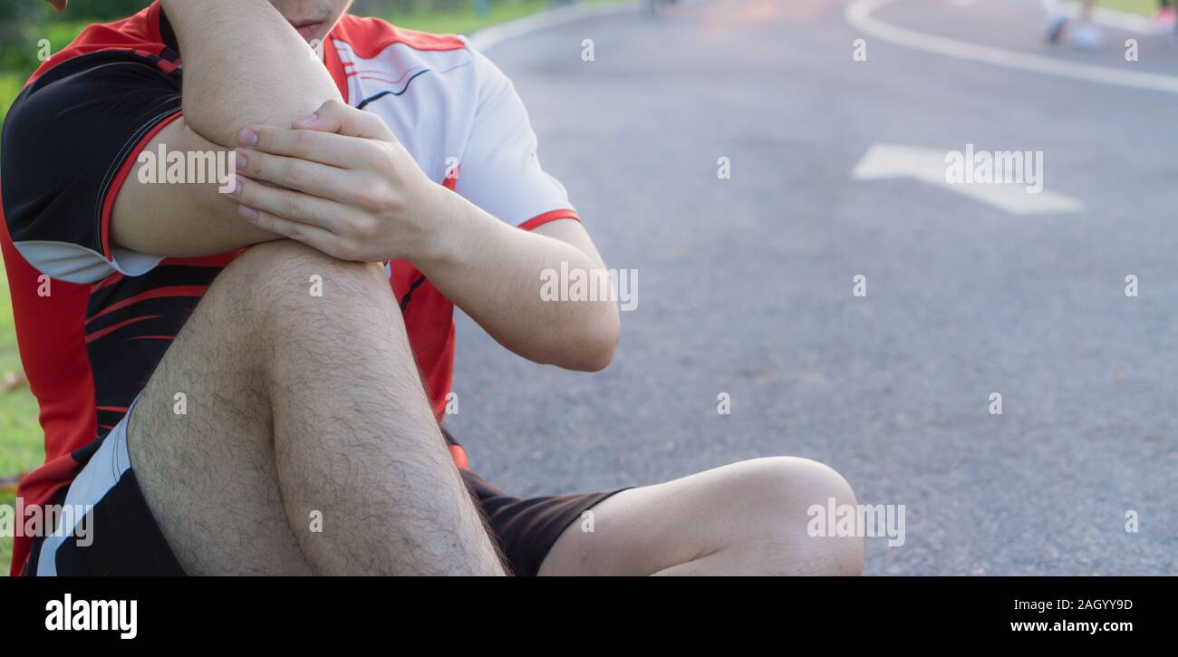A male athlete suffering from arm and elbow pain and injury at the park ...