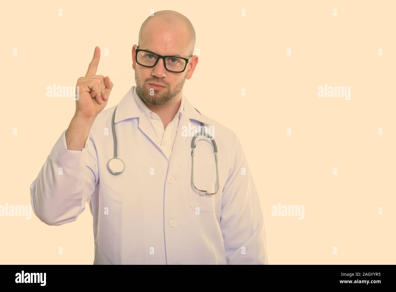 Studio shot of young bald muscular man doctor pointing finger up Stock ...
