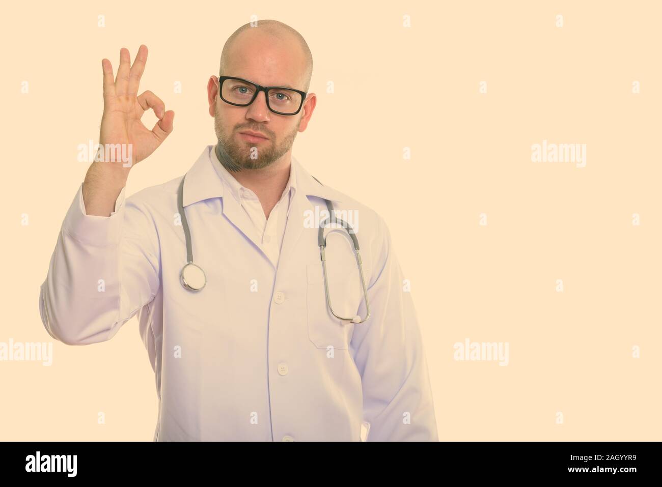 Studio shot of young bald muscular man doctor giving ok sign Stock ...