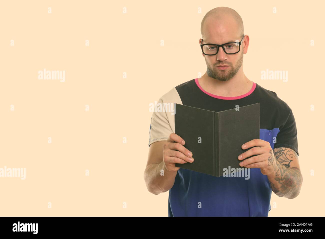 Studio shot of young bald muscular man reading book Stock Photo - Alamy