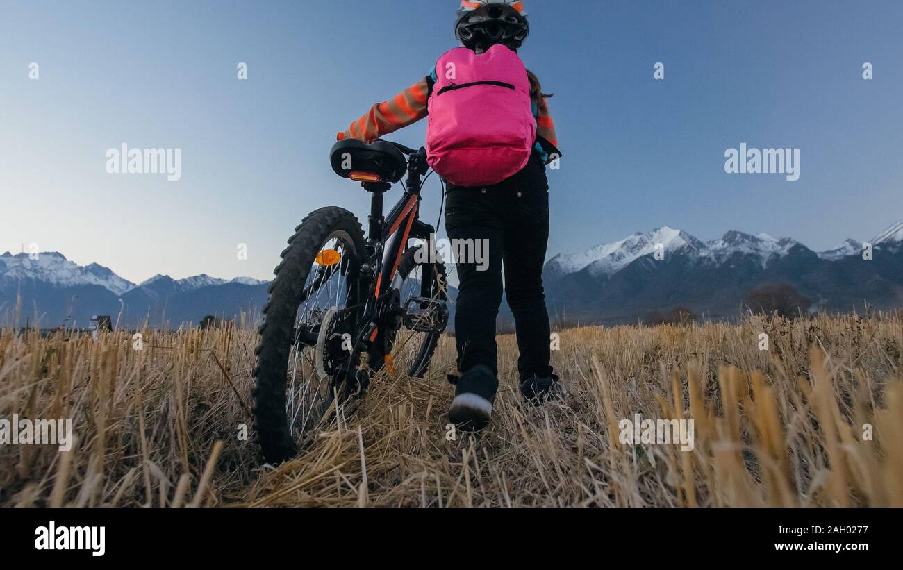 One caucasian children walk with bike in wheat field. Little girl ...