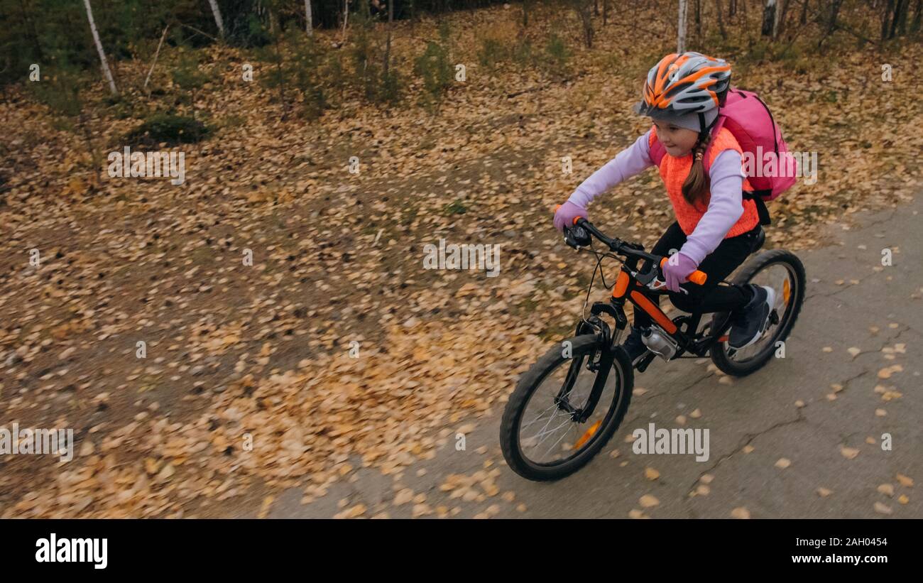 One caucasian children rides bike road in autumn park. Little girl ...