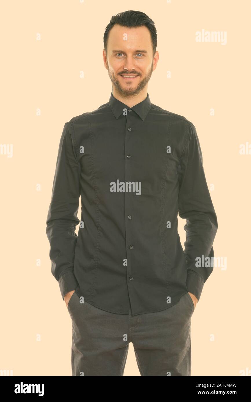 Studio shot of happy young man smiling and standing with hands on ...