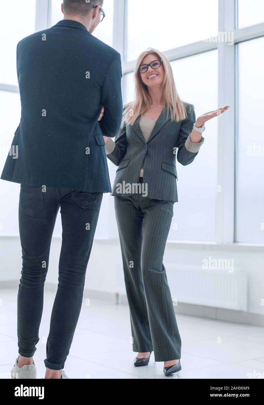 smiling employees discuss something standing in the office corridor ...