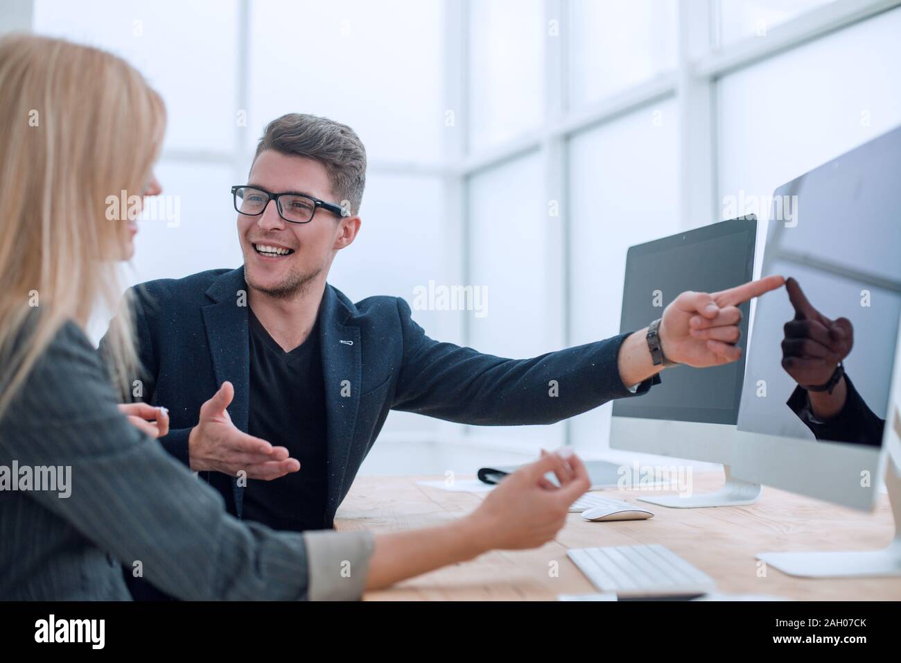 two business colleagues discussing a work project at the desktop Stock ...