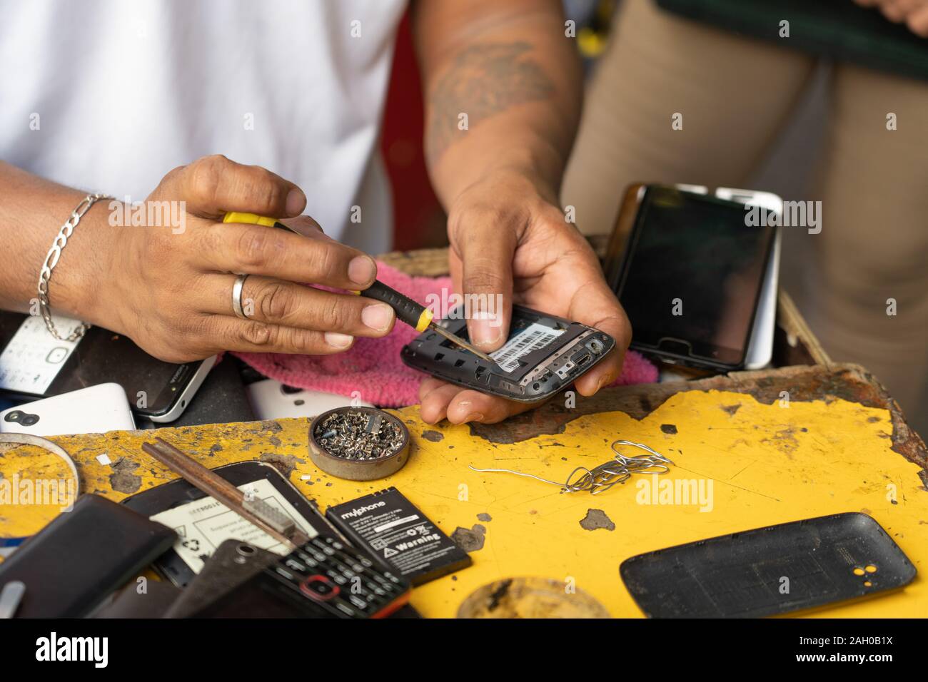 A Filipino man repairing a mobile phone on a side street within Cebu ...