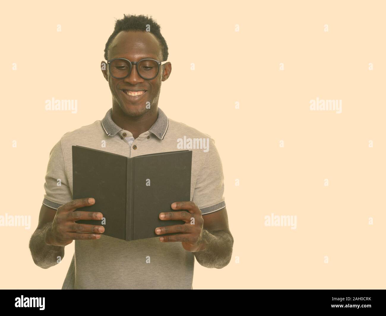 Young happy African man smiling while reading book Stock Photo - Alamy