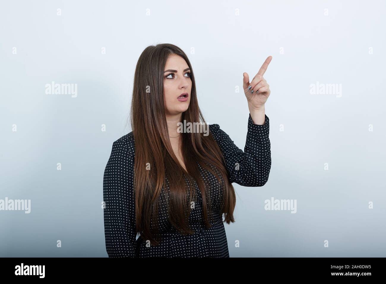 Confused young caucasian woman pointing finger up Stock Photo - Alamy