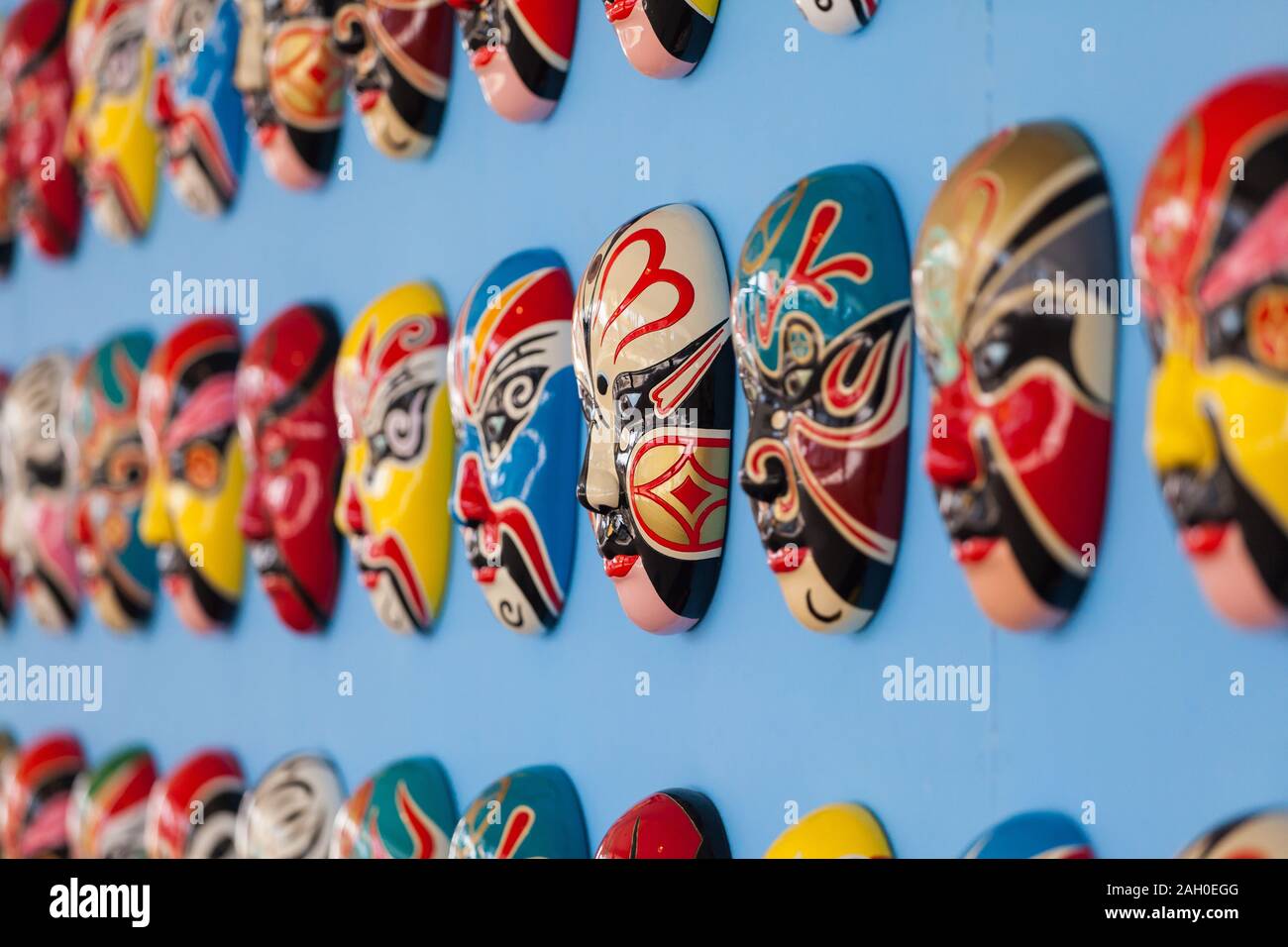 Colourful hand painted Chinese opera masks hang up neatly on a blue ...
