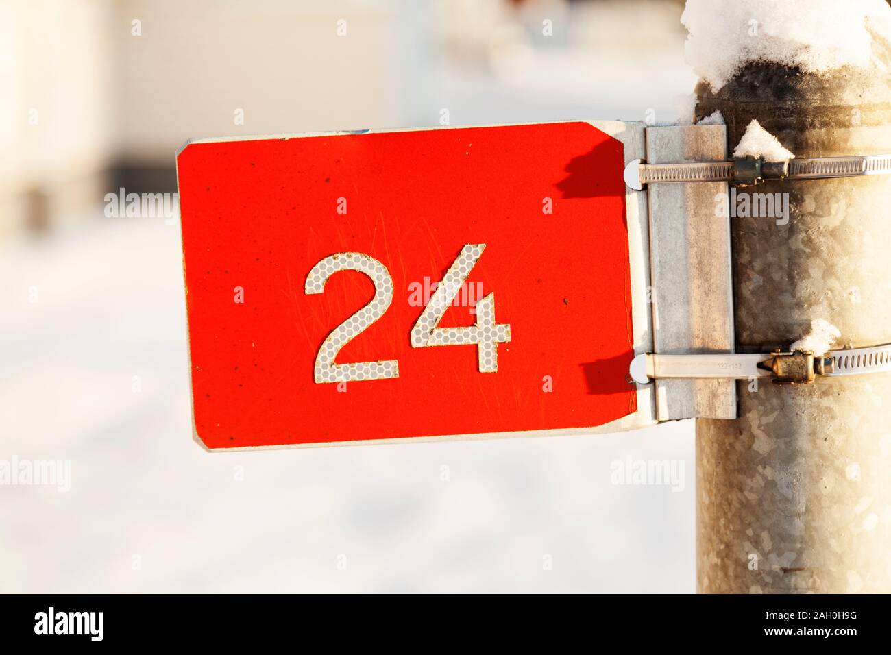 red sign with the number twenty four in white with winter background ...