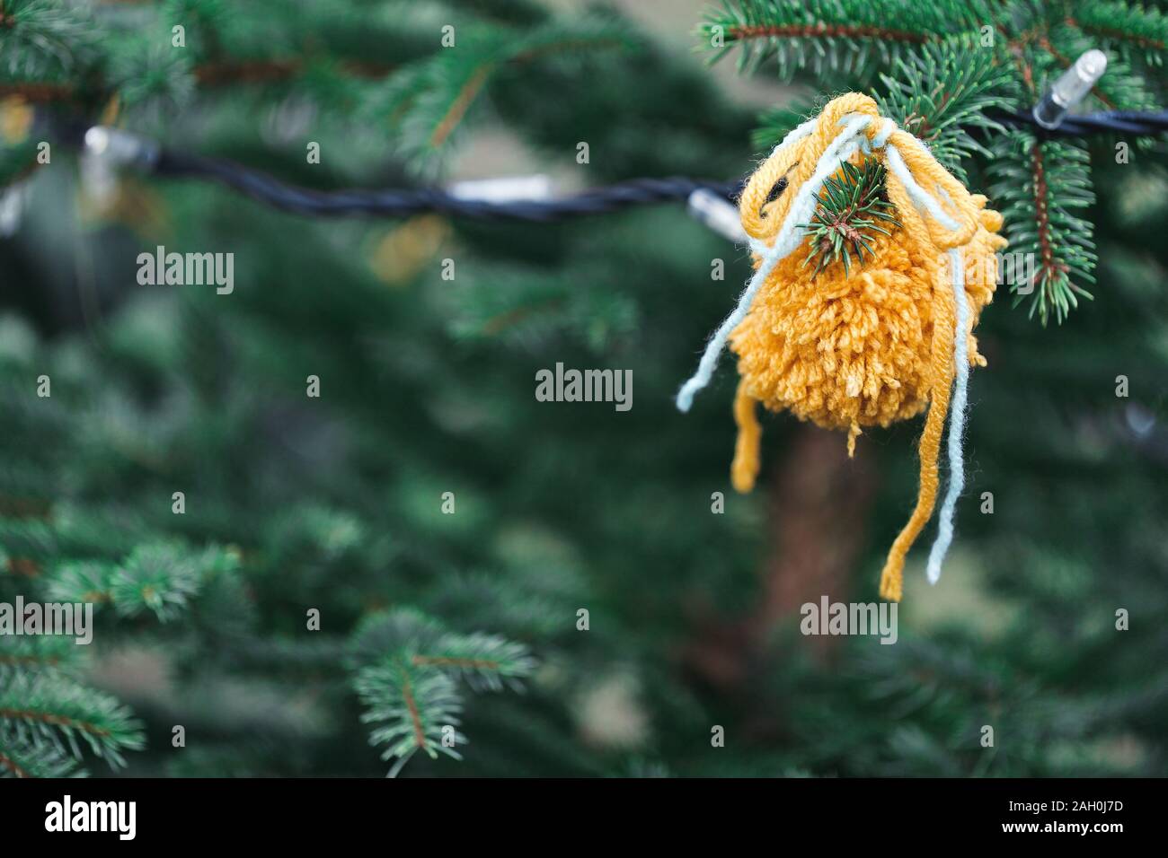 Wool handmade decoration on a Christmas tree outdoor. Diy yarn crafts ...