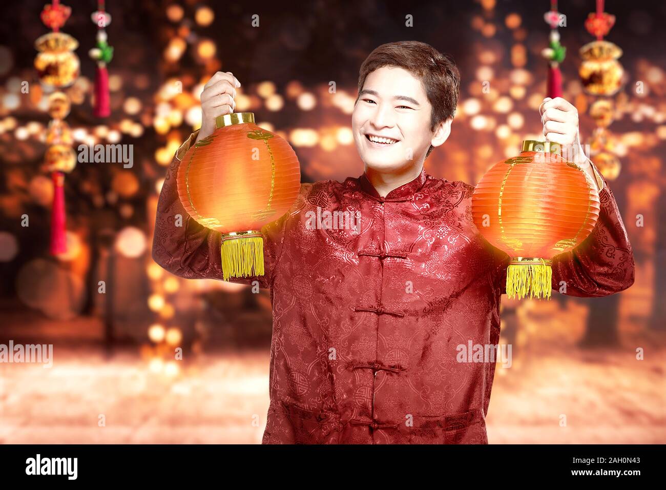 An Asian Chinese man in a cheongsam dress holding Chinese lantern ...