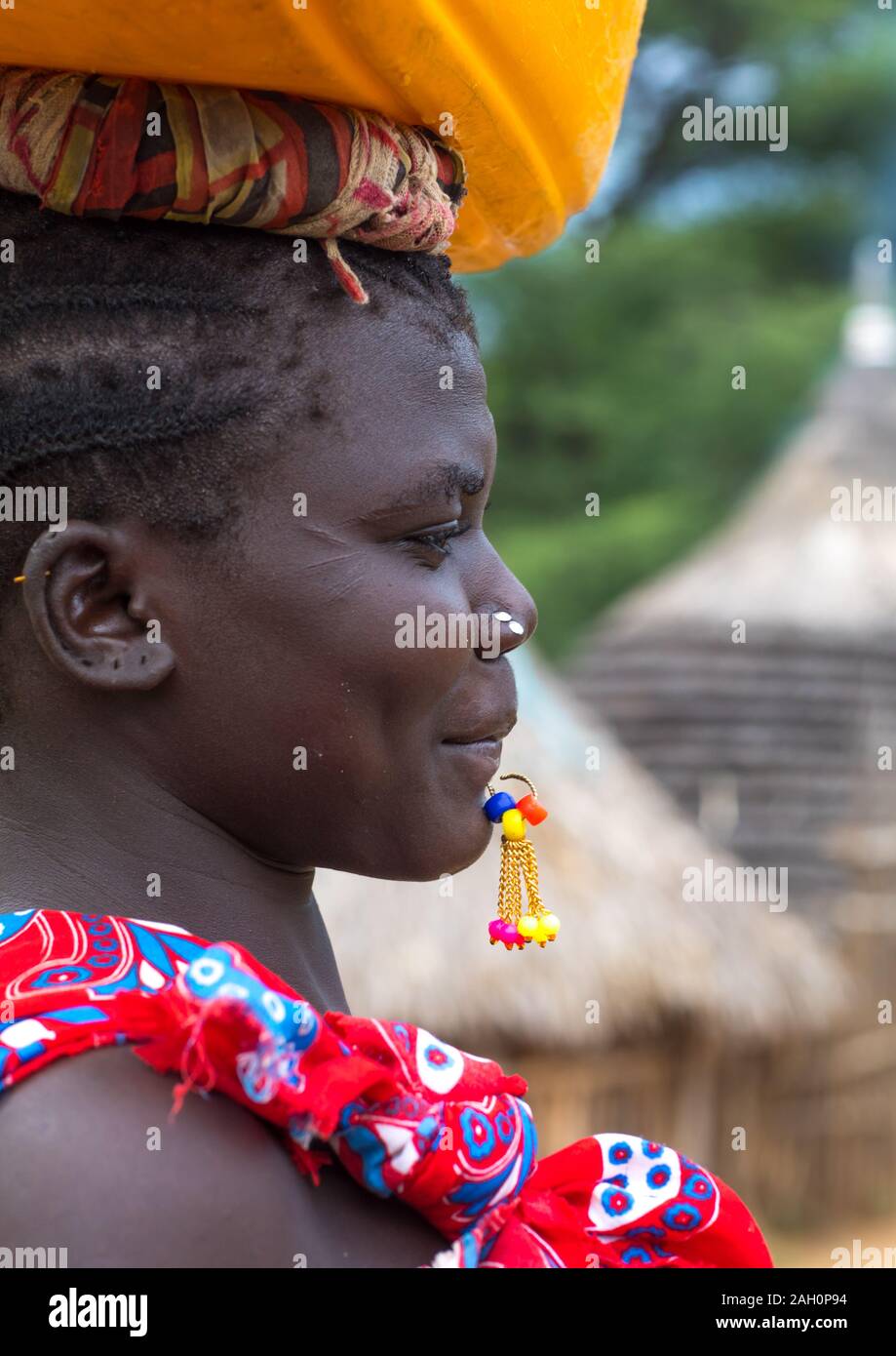 Portrait of a Larim tribe woman carrying a yellow jerrican on the head ...