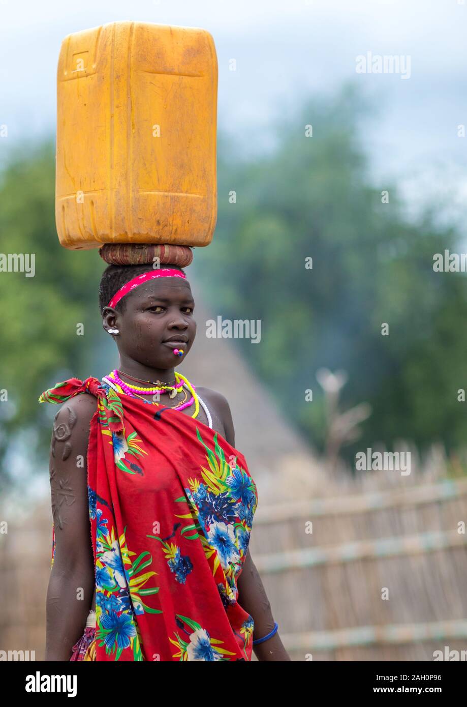 Portrait of a Larim tribe woman carrying a yellow jerrican on the head ...