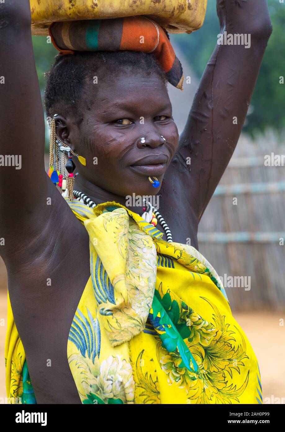 Portrait of a Larim tribe woman carrying a yellow jerrican on the head ...