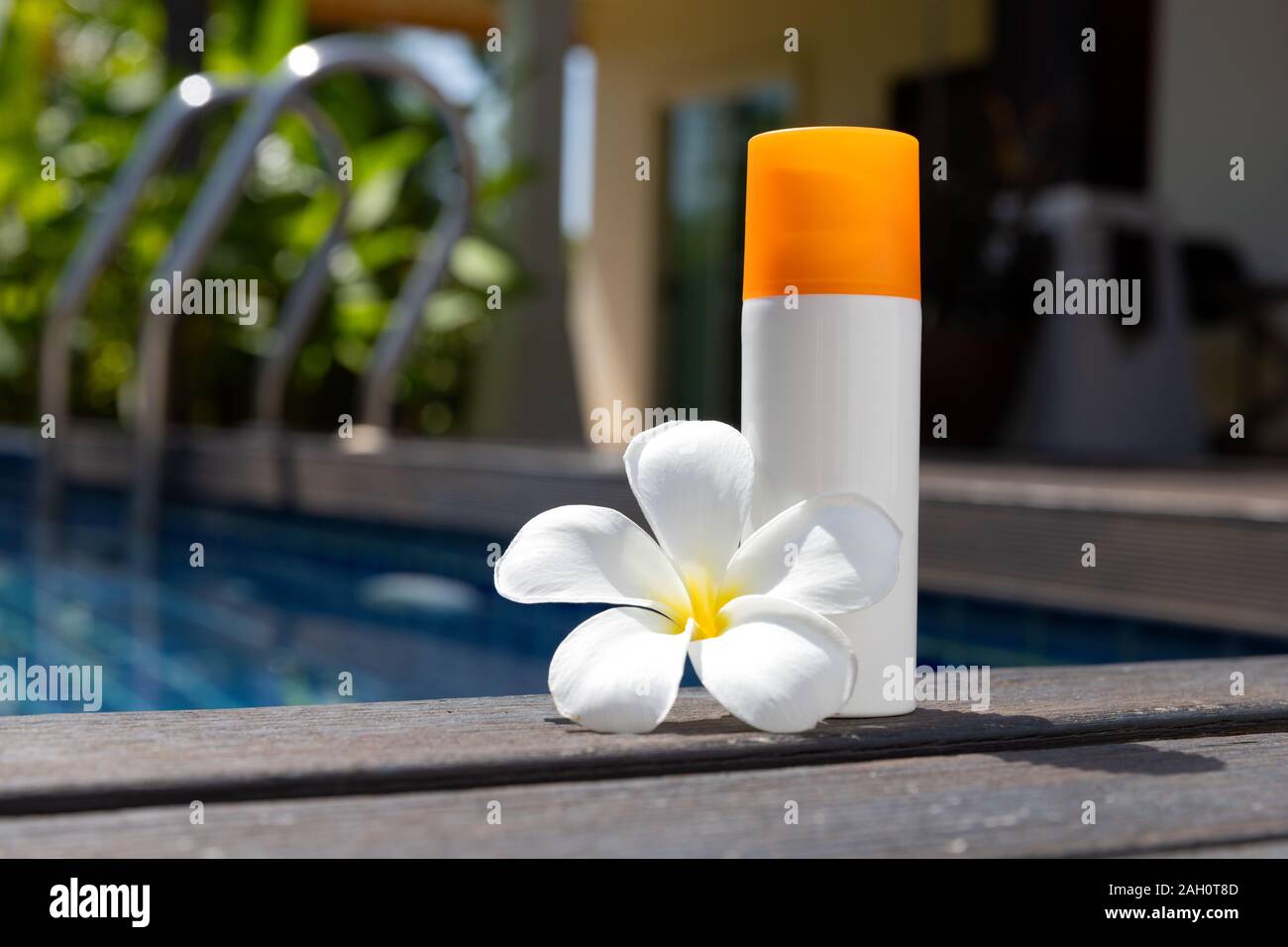 Sunscreen cream and tropical flower near swimming pool. Summer ...