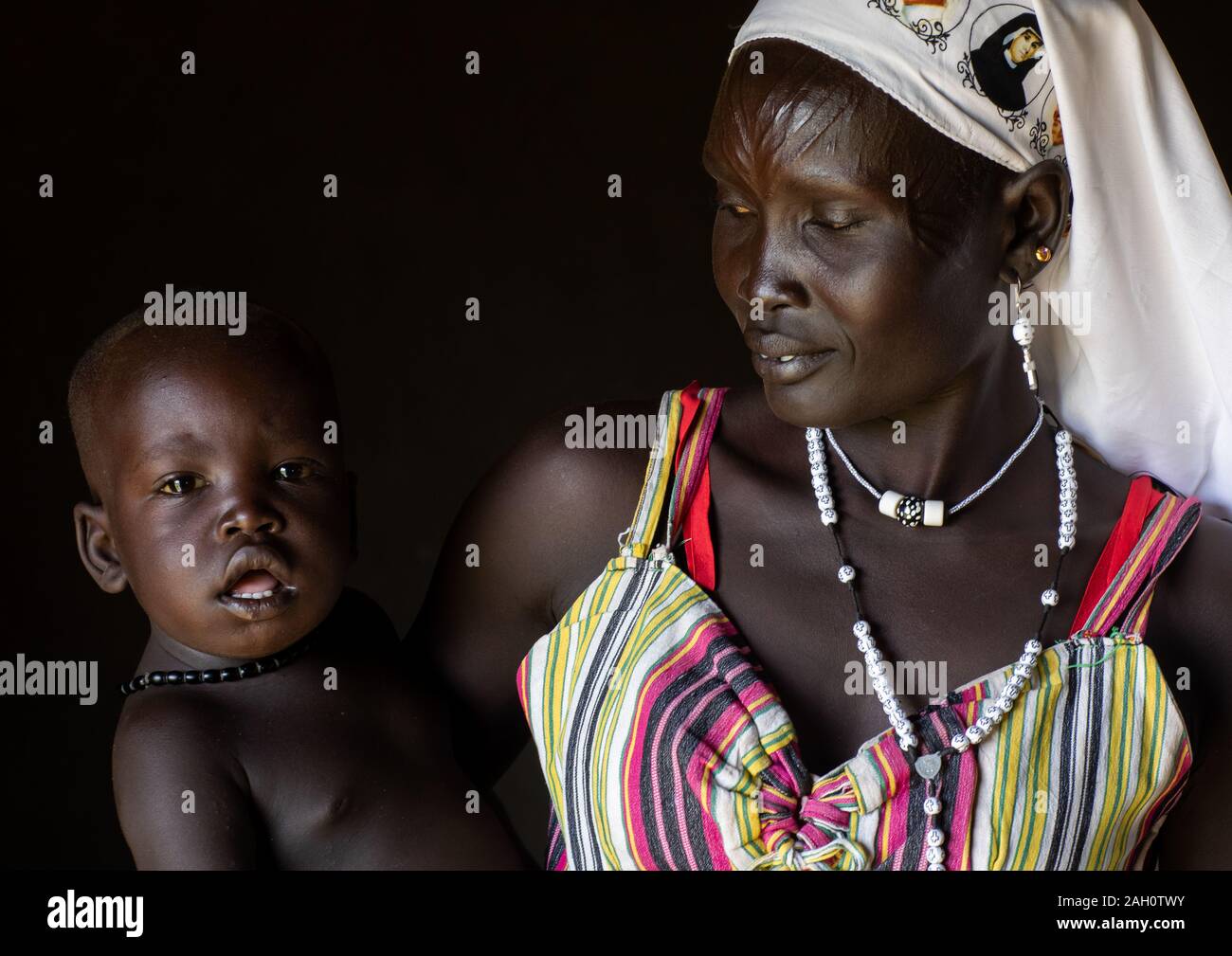 Portrait of a Mundari tribe nun with scarifications on the forehead with her child, Central ...