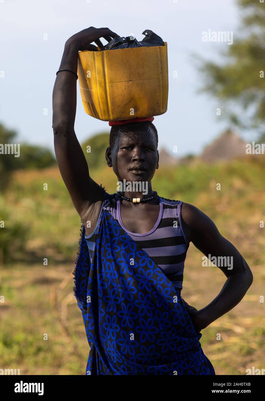 Portrait of a Mundari tribe woman with scarifications on the forehead carrying a jerrican ...
