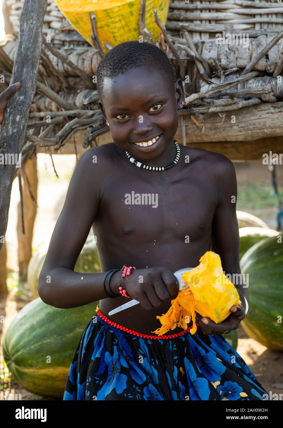 Portrait of a Mundari tribe girl cutting a pumpkin, Central Equatoria ...