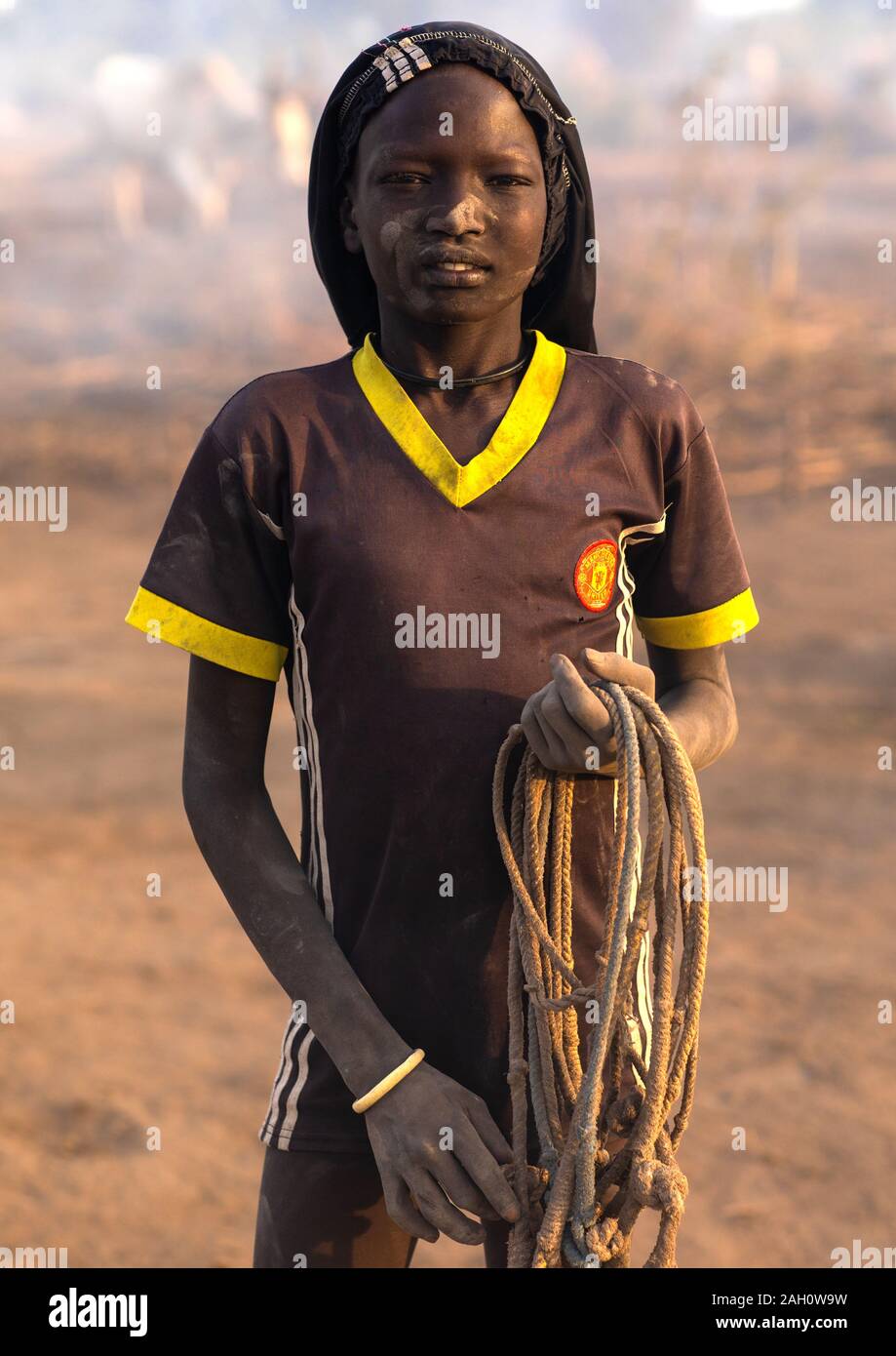 Portrait of a Mundari tribe boy with ropes for the cows wearing a football shirt, Central ...