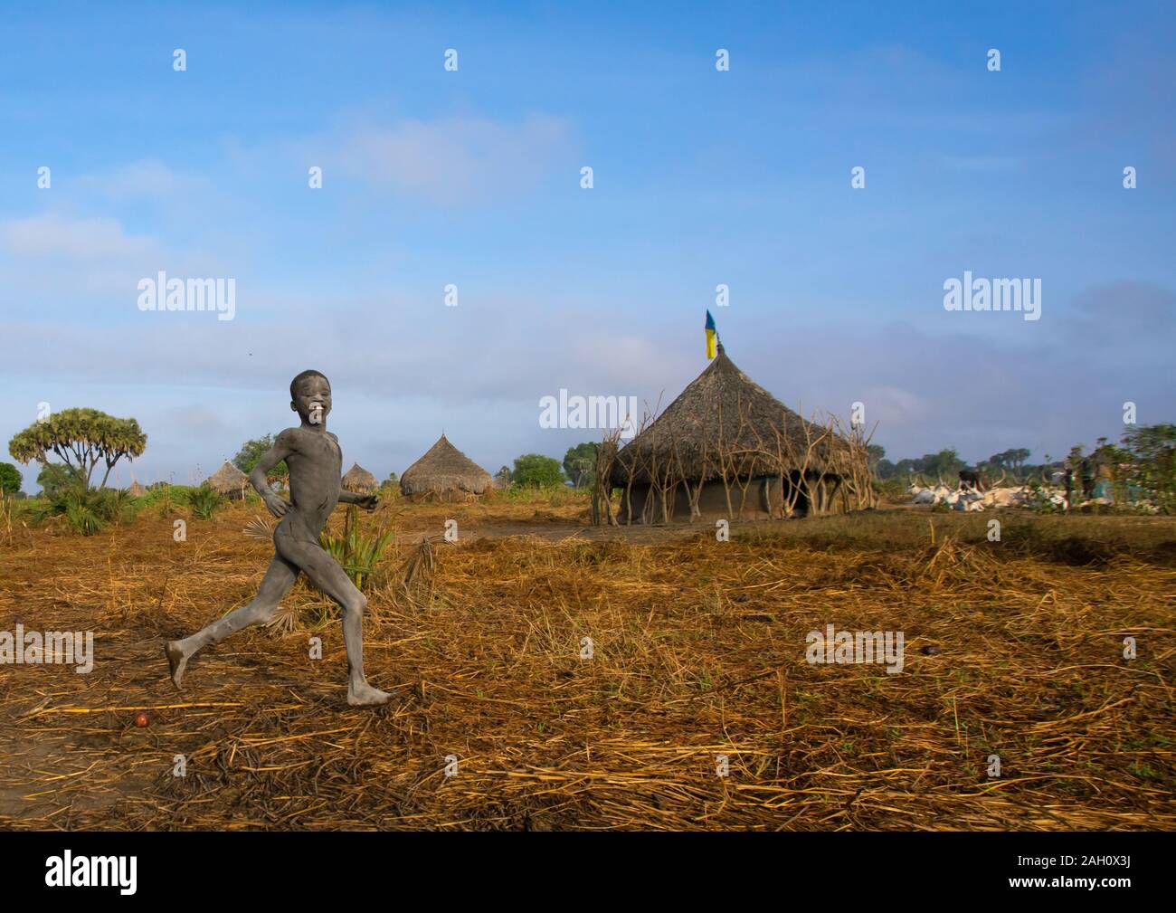 Boy running in front of a traditional Mundari tribe village, Central ...