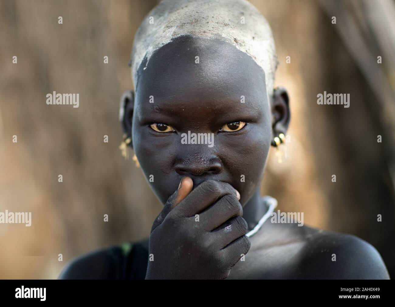 Portrait of a beautiful Mundari young woman with ash on the head to dye ...