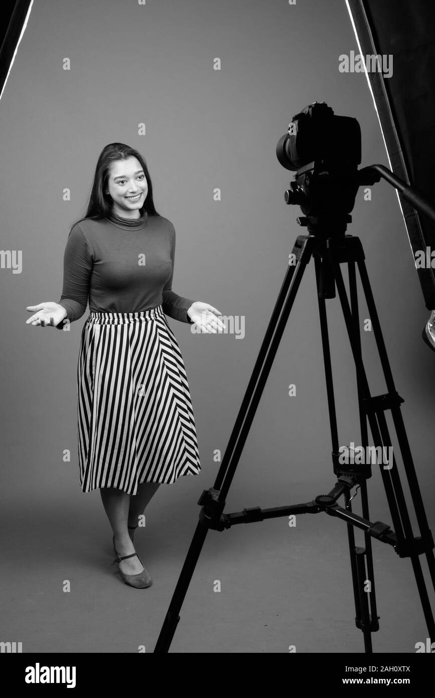 Young beautiful Indian woman vlogging against gray background Stock ...