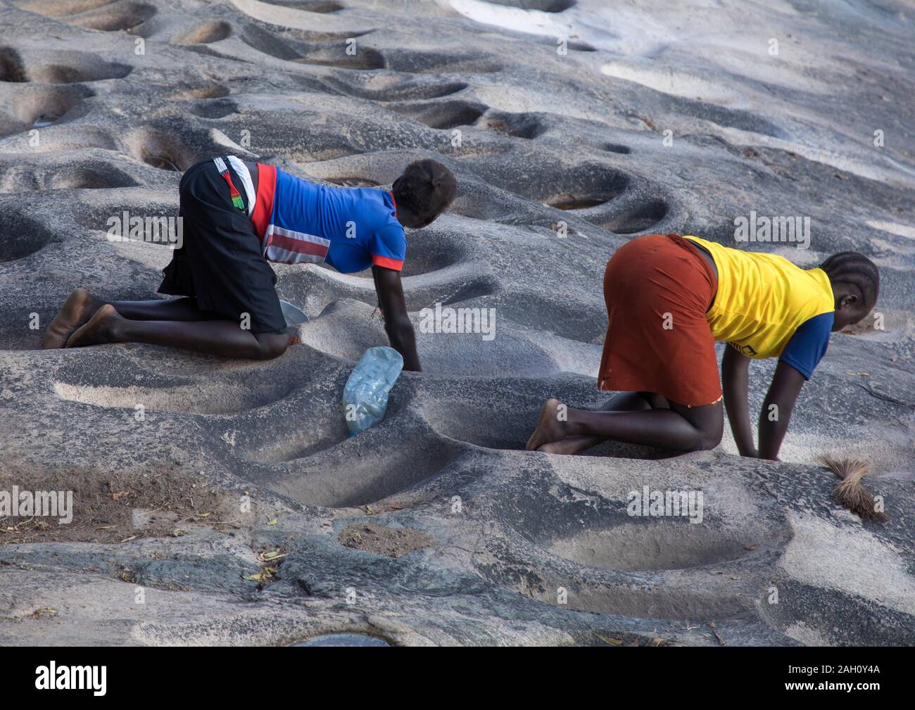 Lotuko tribe woman grinding grains in a hole in the rock, Central ...