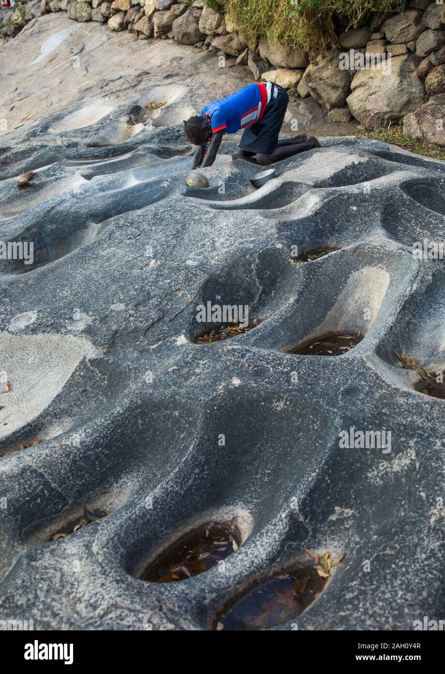 Lotuko tribe woman grinding grains in a hole in the rock, Central ...