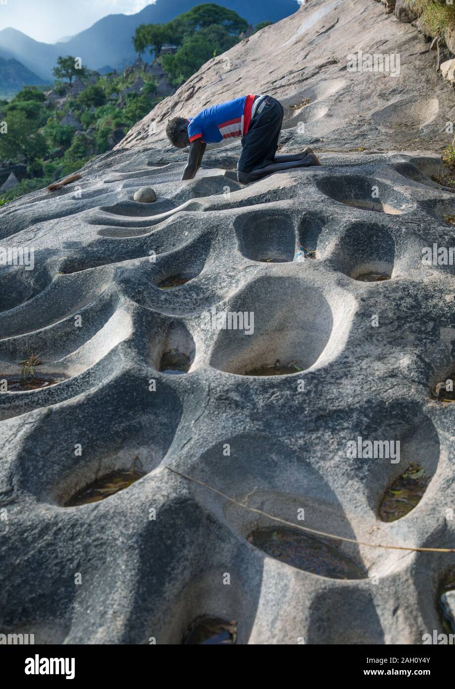 Lotuko tribe woman grinding grains in a hole in the rock, Central ...