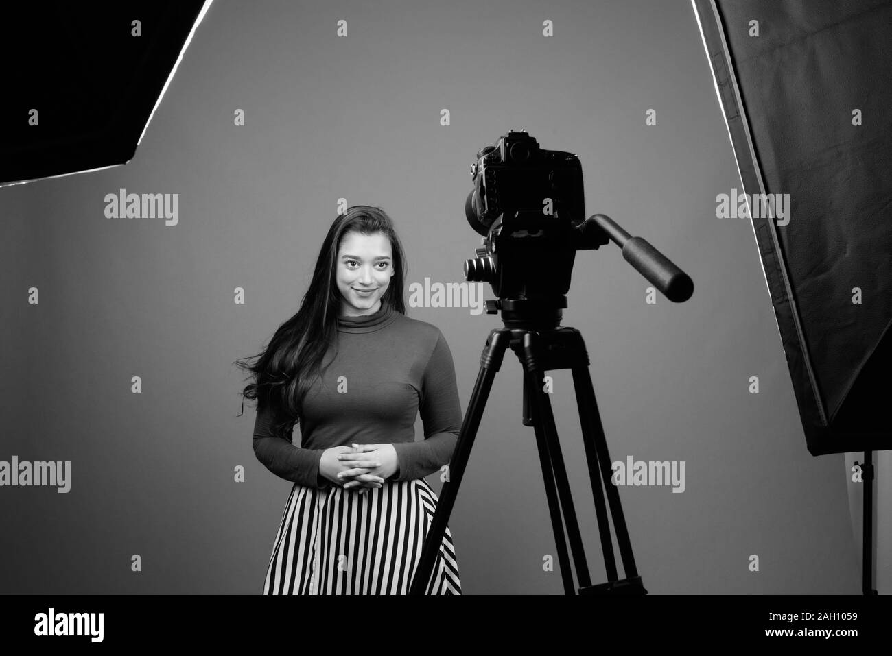 Young beautiful Indian woman vlogging against gray background Stock ...