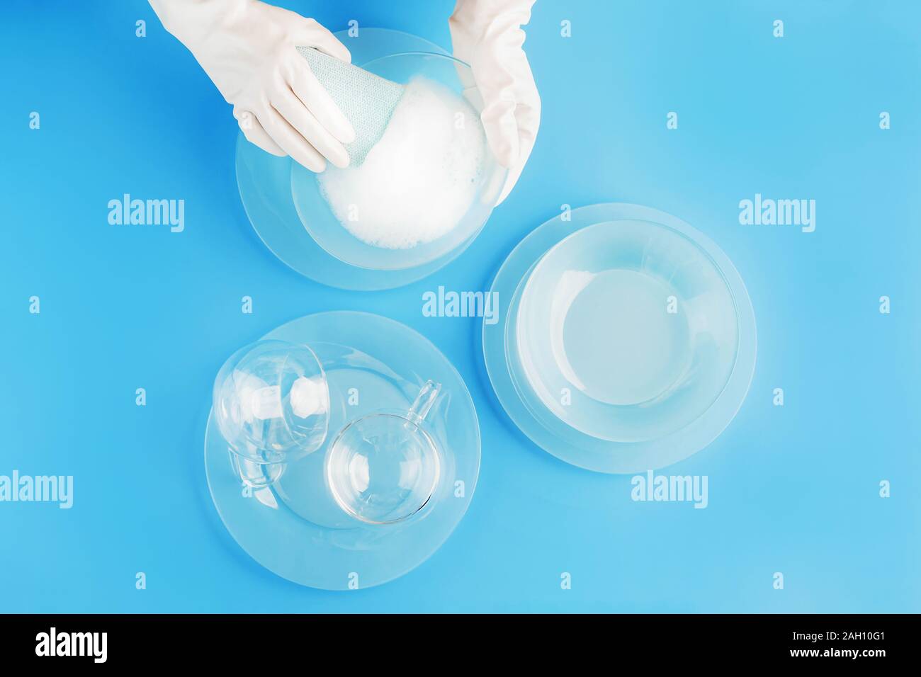 Female hands in pearly white gloves washing beautiful light blue glass ...