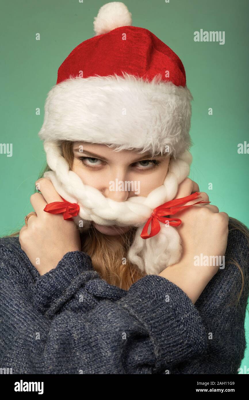 serious miss santa looks at camera on green background, covers her face ...