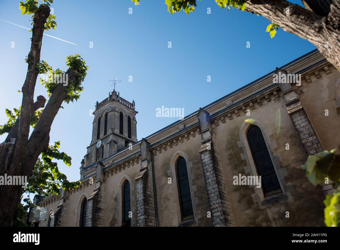 small cathedral with green trees next to it under hot summer sun in ...
