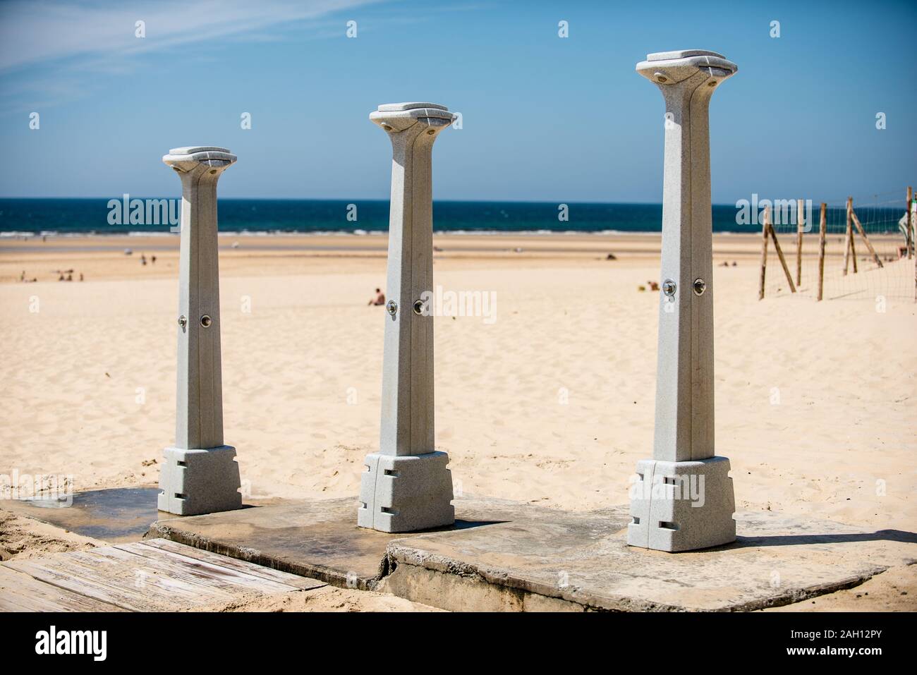 three showers in the sand on the beach with blue sea in the background ...