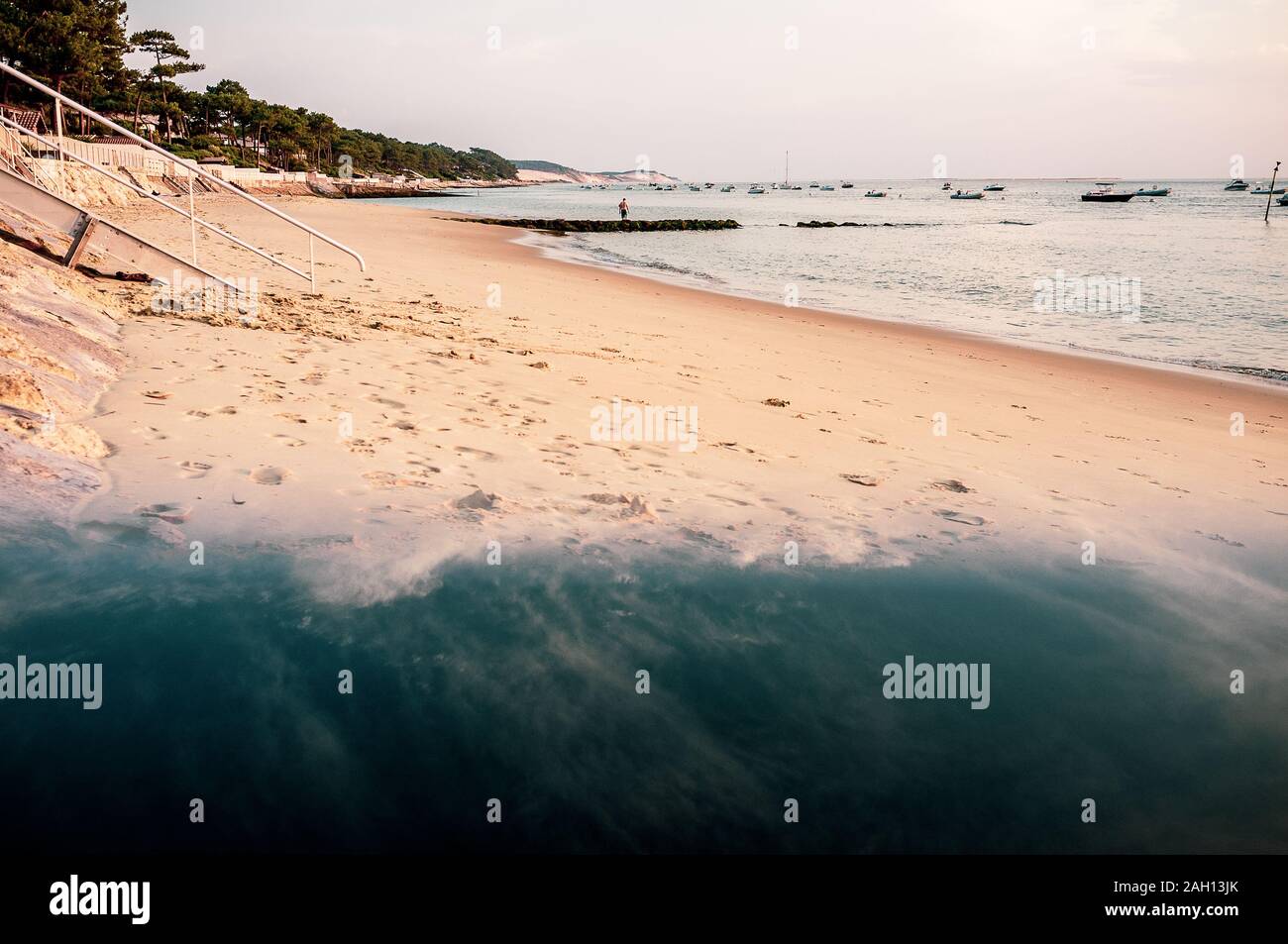 reflection of sky on the beach with stairway and trees in the ...