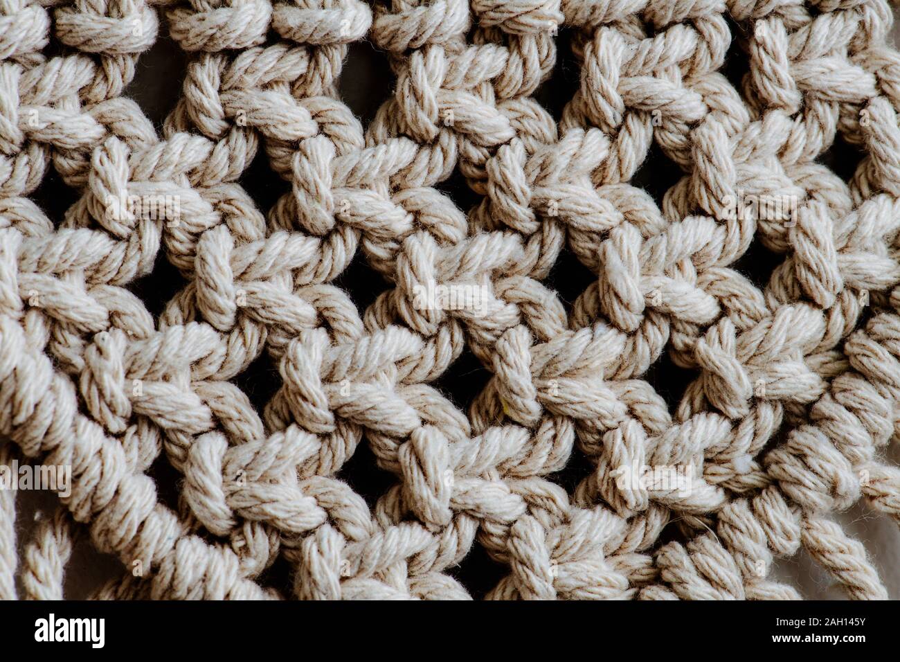Texture of open-weaved macrame tapestry up close. Knots and ropes in a ...
