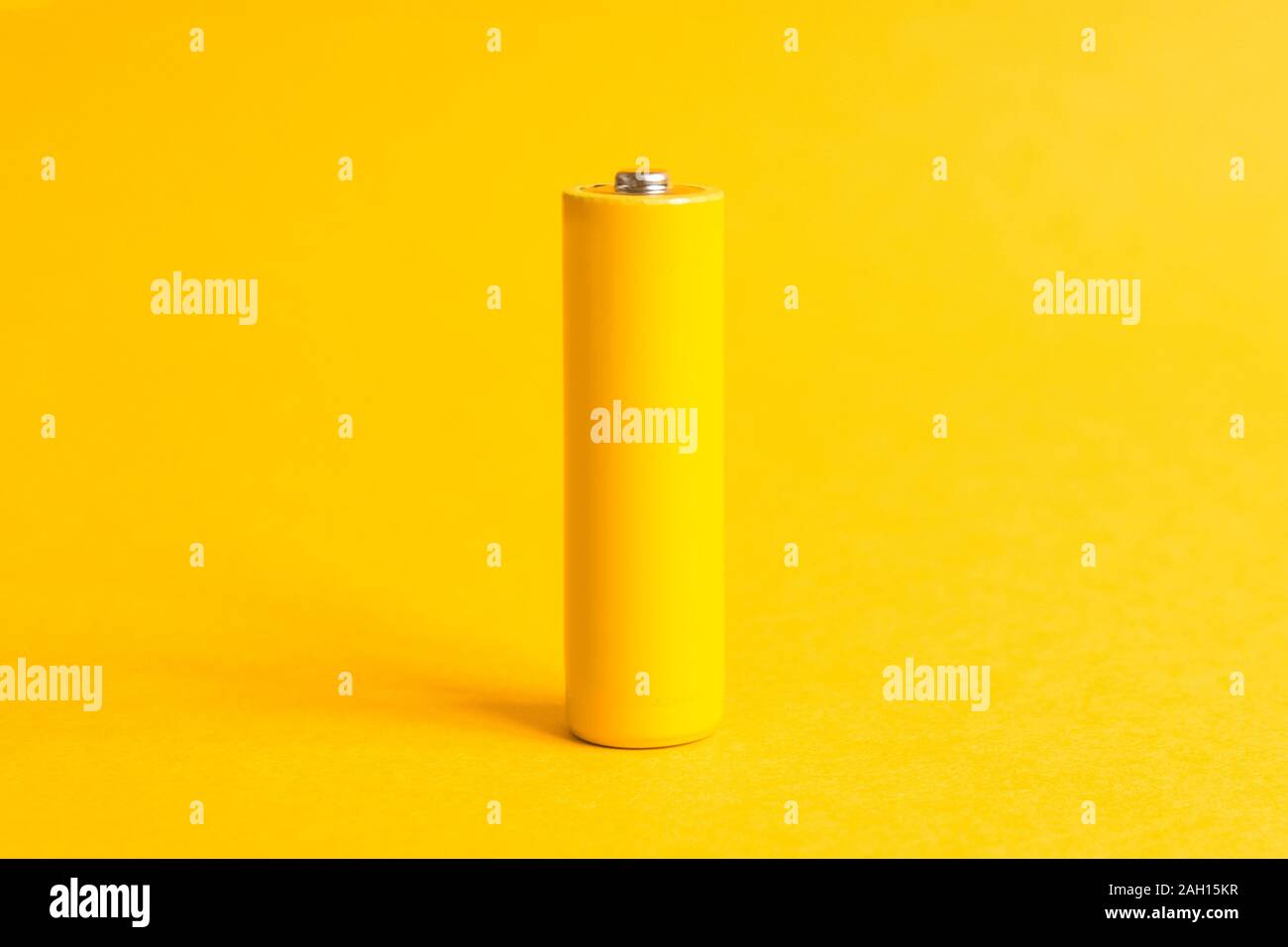 Single yellow battery on a yellow pastel background Stock Photo - Alamy