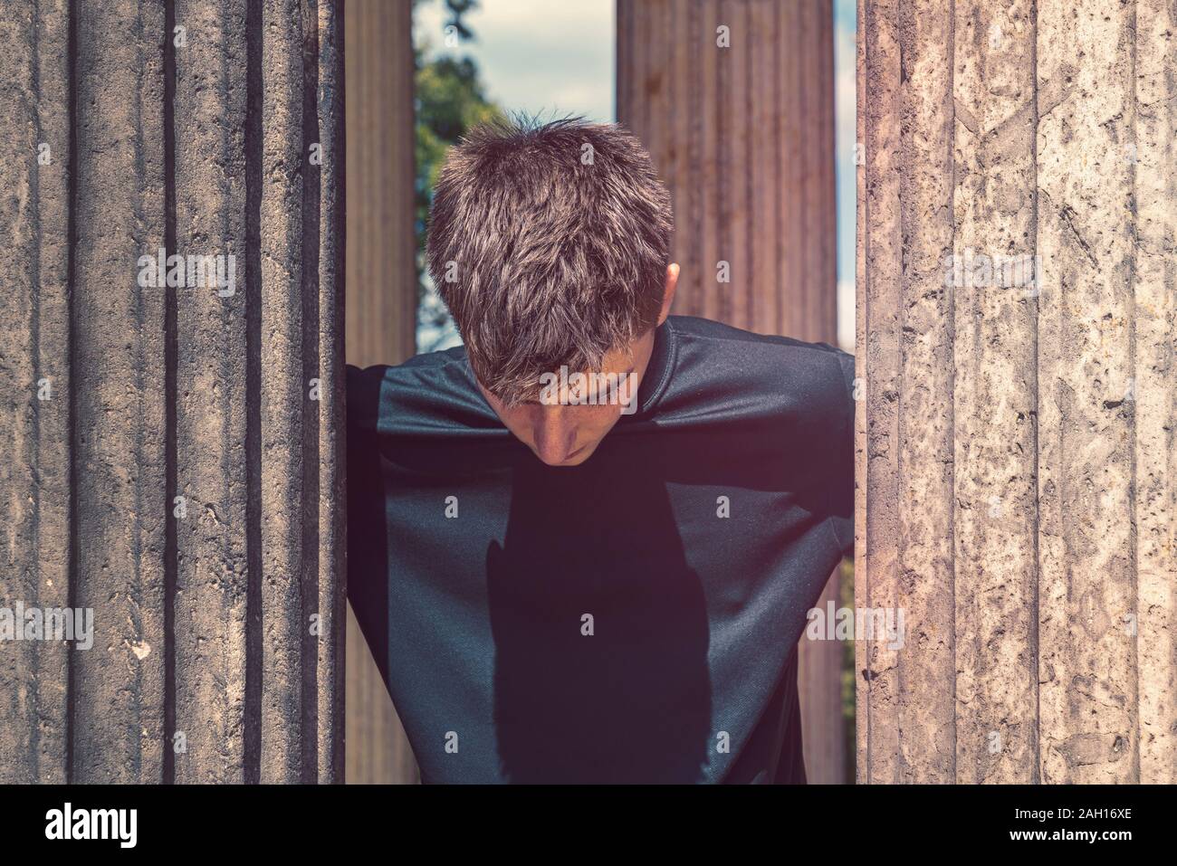 portrait of a young man standing between antique columns and looking ...