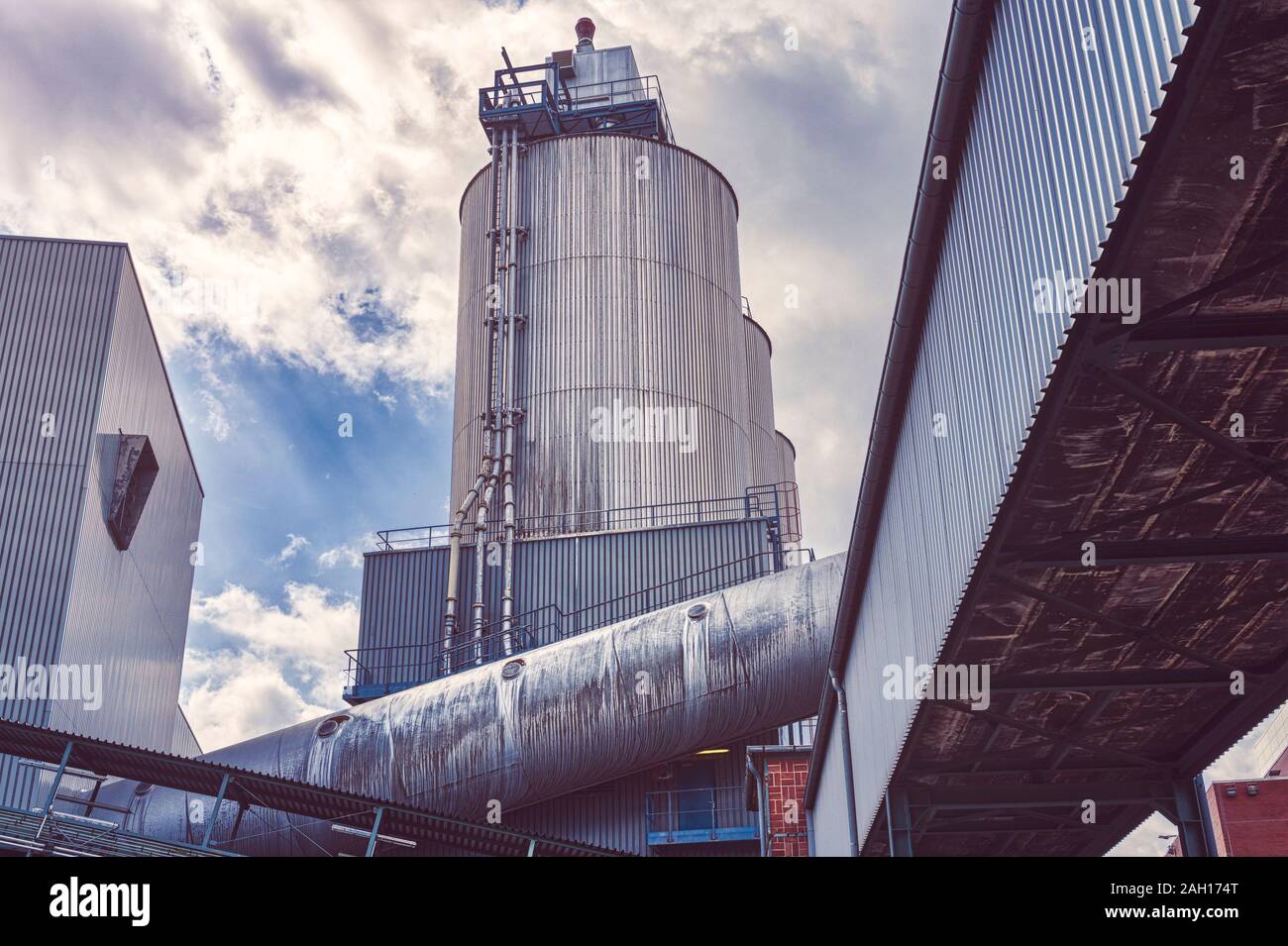 three silos and a large pipe of a factory with dramatic sky Stock Photo ...