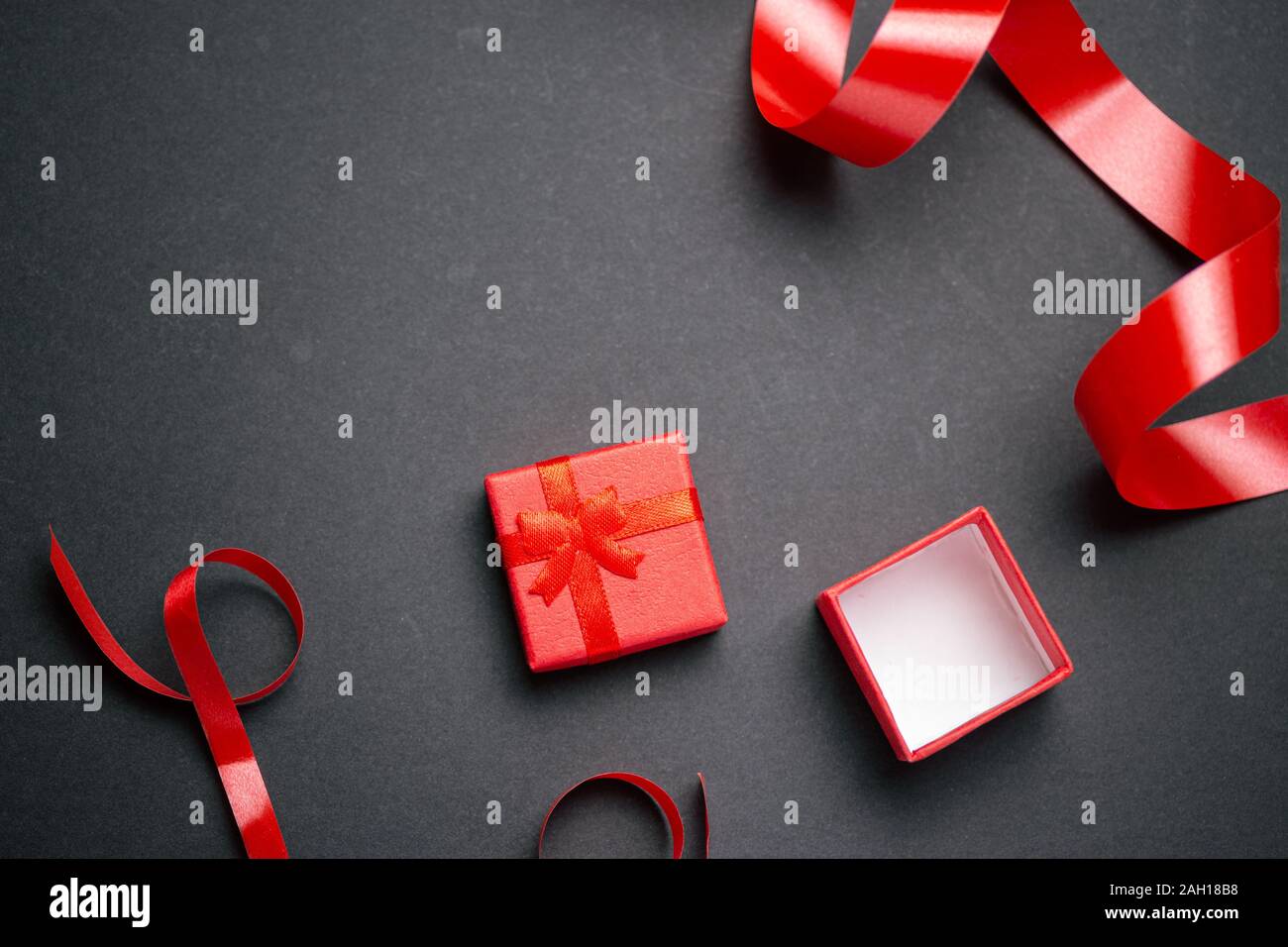 Top view of red gift box with many red gift bow over black background ...