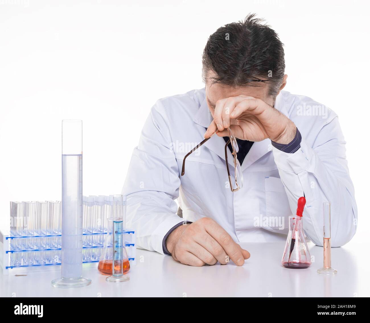 Tired young doctor trying to focus. Holding his head and eyeglasses ...